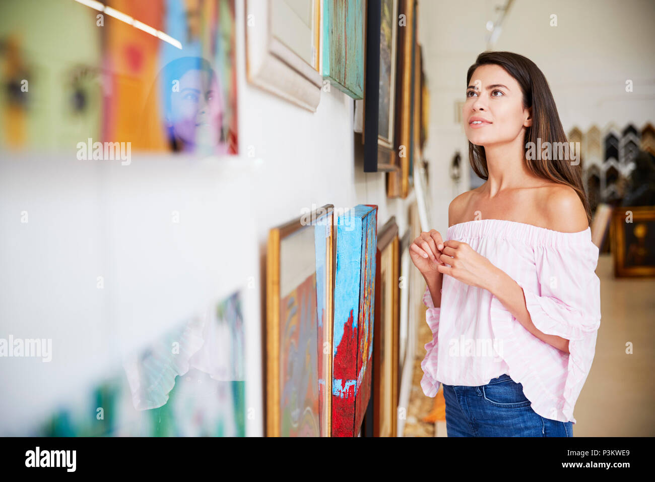 Woman Looking At Paintings In Art Gallery Stock Photo - Alamy
