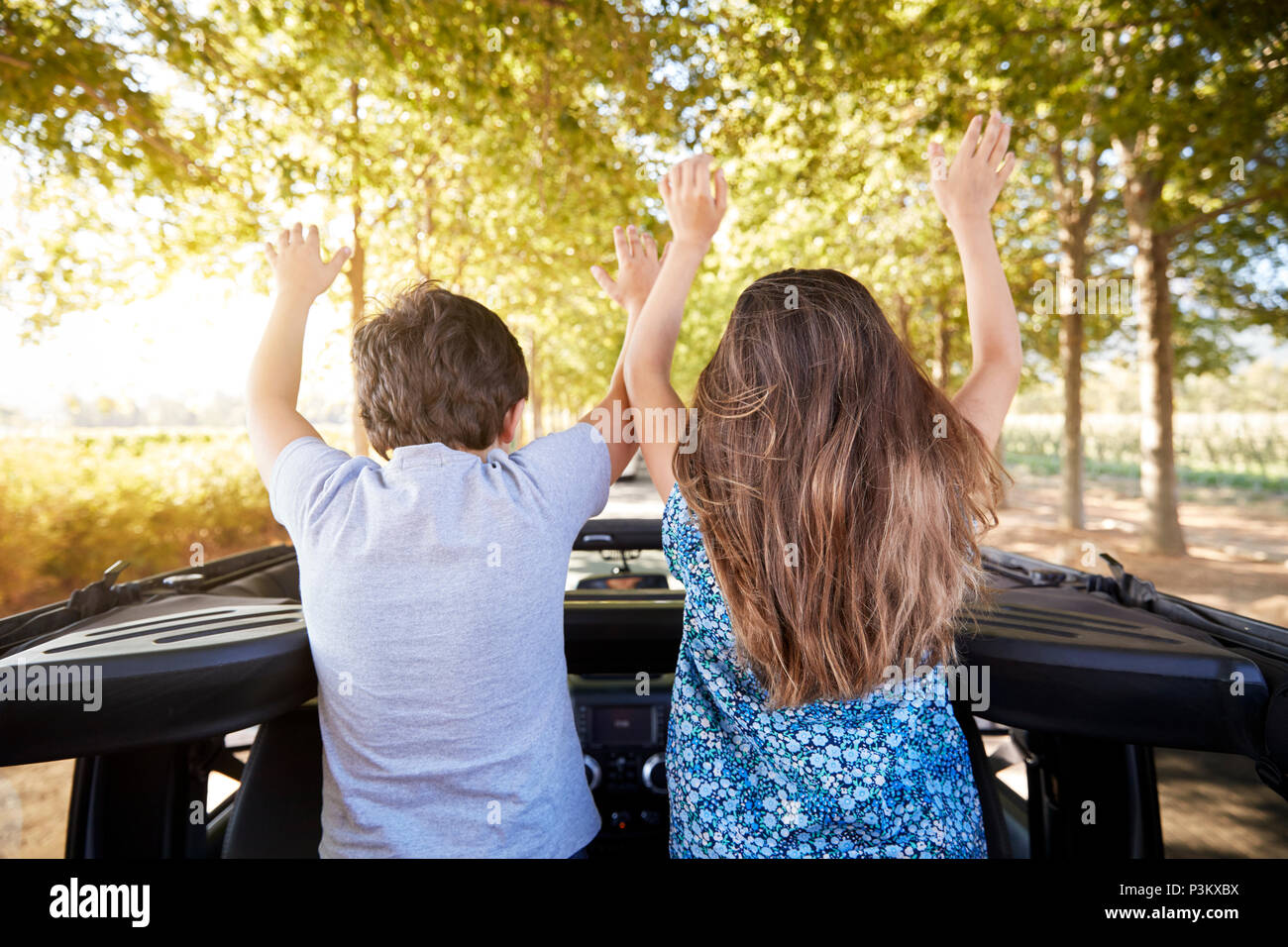 Children Standing Up In Back Of Open Top Car On Road Trip Stock Photo ...