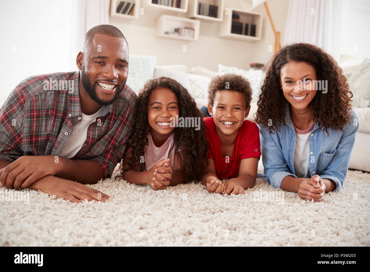 Portrait Of Family Lying On Rug In Lounge At Home Stock Photo - Alamy