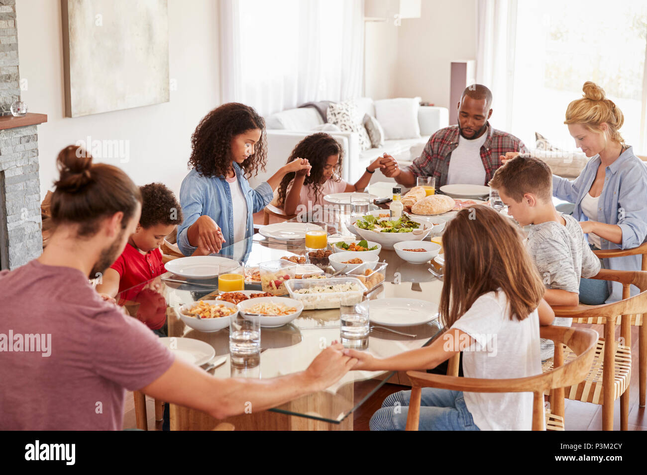 Two Families Praying Before Enjoying Meal At Home Together Stock Photo ...