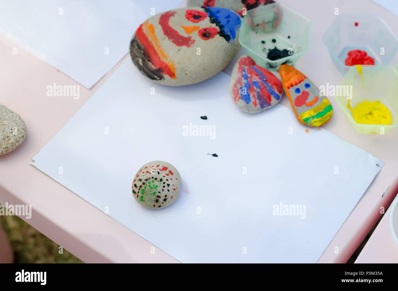 child painting pebbles with brush Stock Photo - Alamy