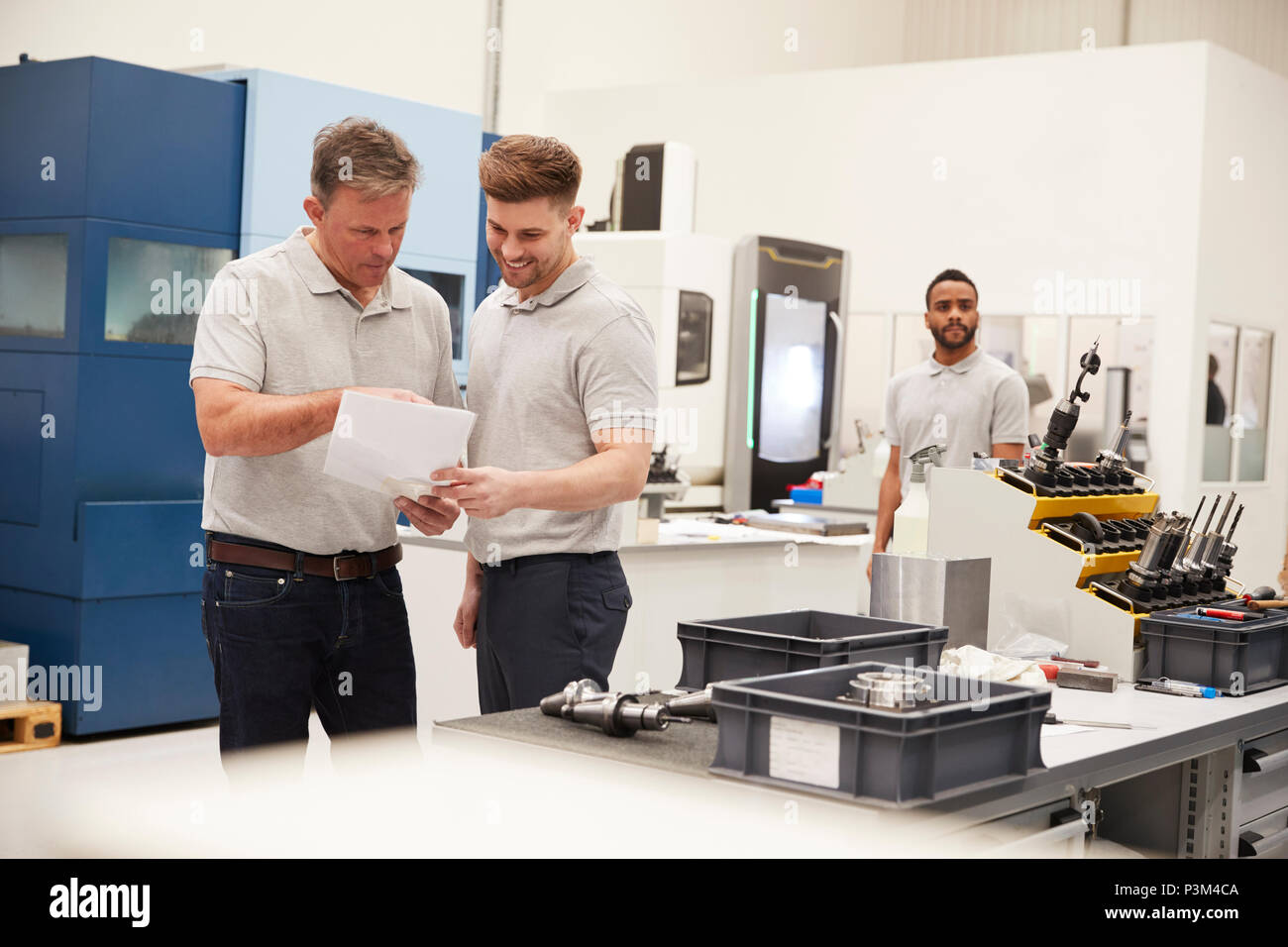 Engineer And Apprentice Meet On Floor Of Engineering Workshop Stock ...
