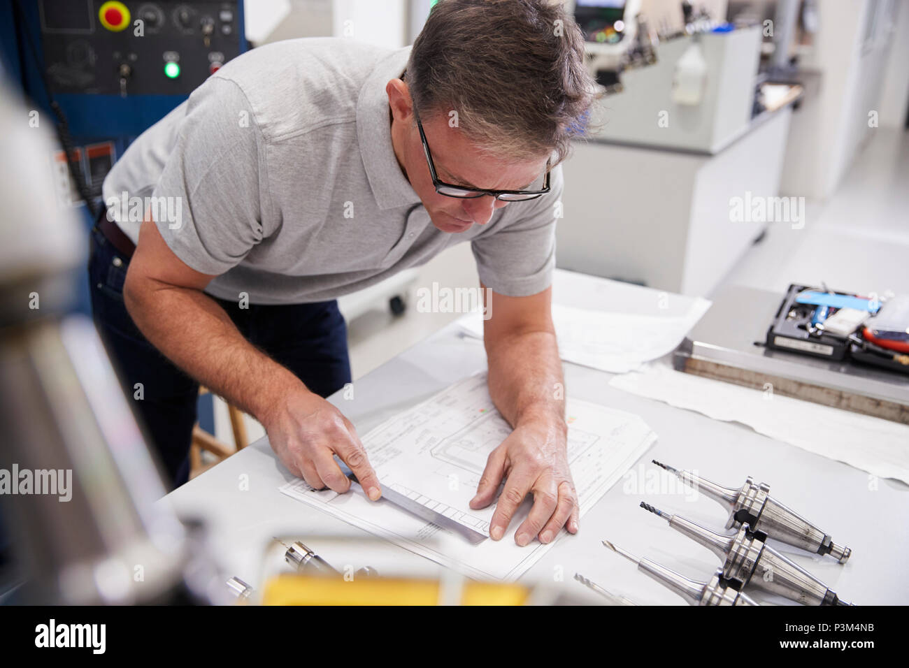 Male Engineer Measuring CAD Drawings In Factory Stock Photo - Alamy