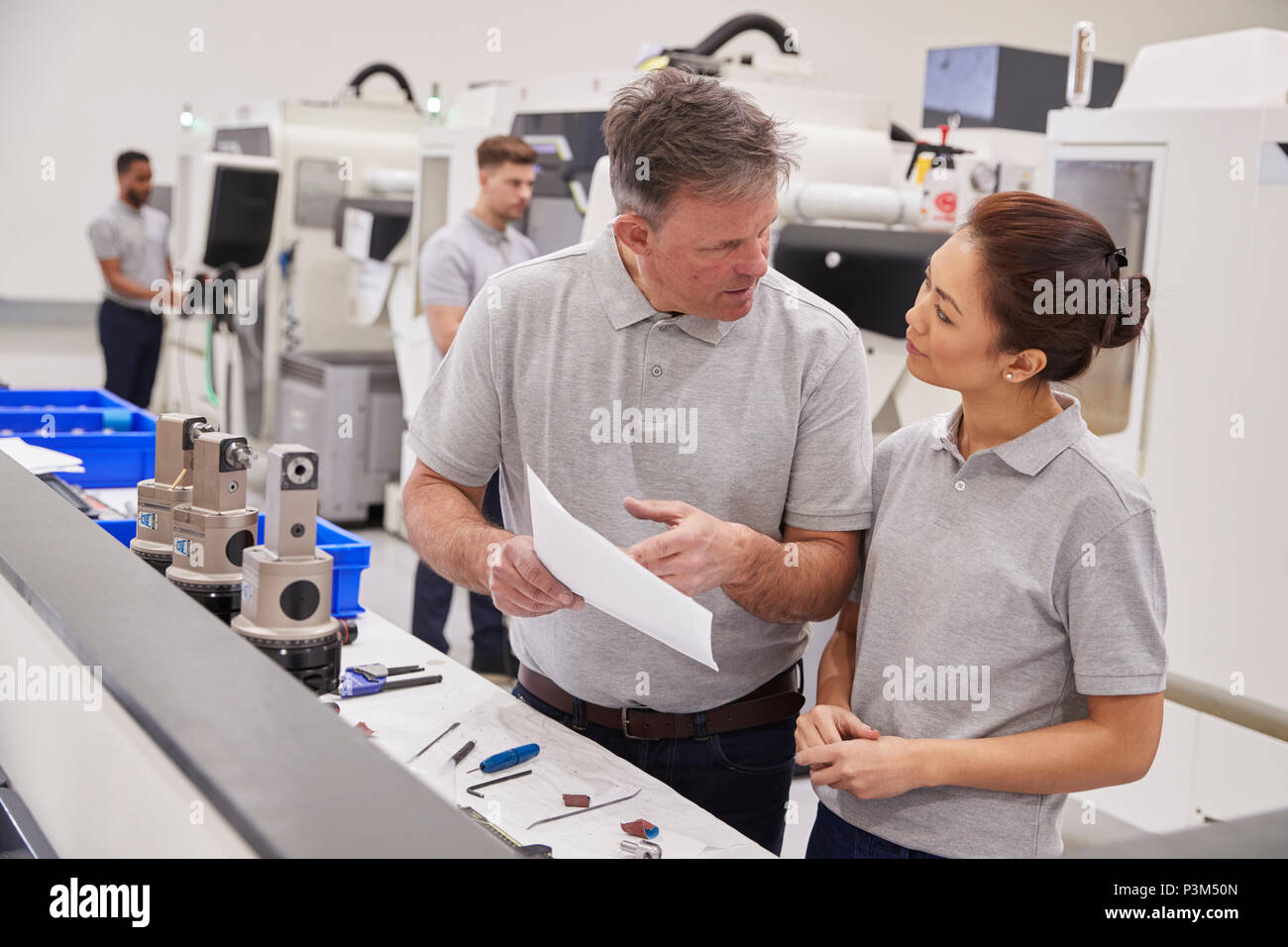 Engineer And Female Apprentice Discussing Job Sheet In Factory Stock ...