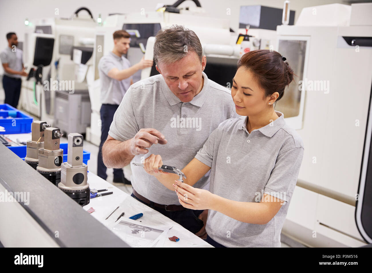 Engineer And Female Apprentice Measuring Components In Factory Stock ...