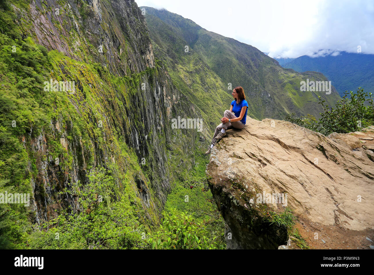 Young woman enjoying the view of Inca Bridge and cliff path near Machu ...