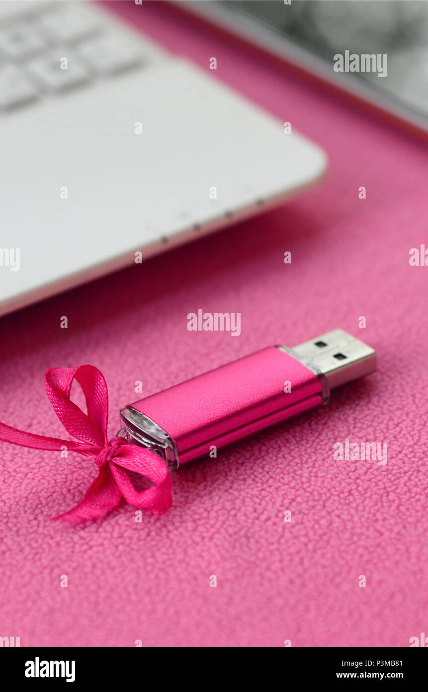 Brilliant pink usb flash memory card with a pink bow lies on a blanket ...