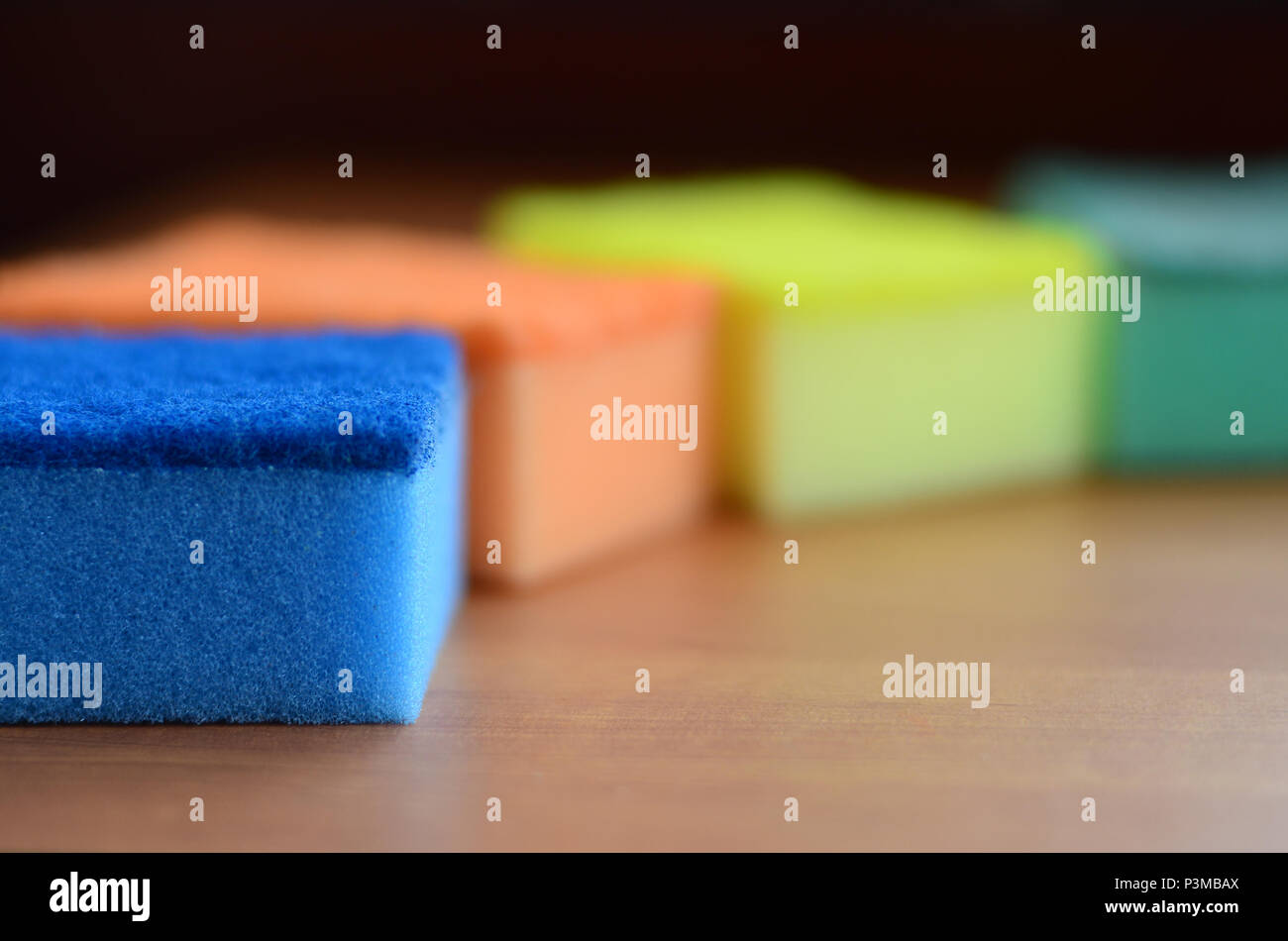 A few kitchen sponges lie on a wooden kitchen countertop. Colorful ...