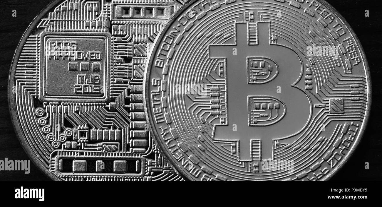 Two new silver physical bitcoins lies on dark wooden backgound, close ...