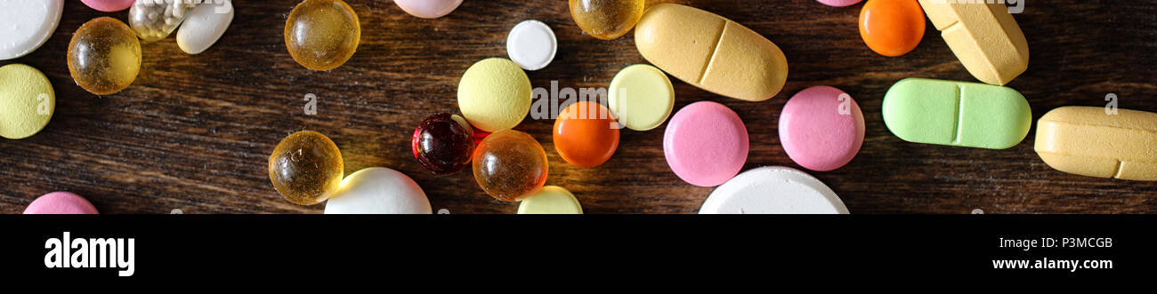 Medical background of various colorful medications on a textured wooden ...