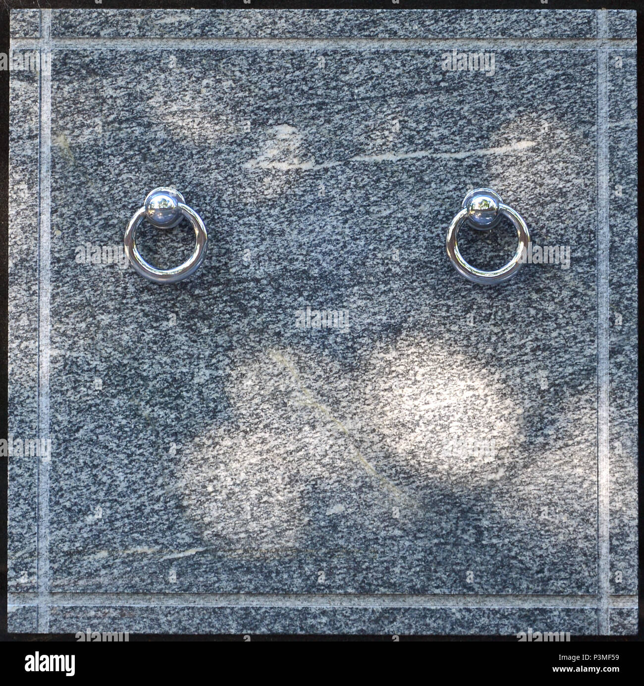 The front part of the granite crypt with metal ring handles in the ...