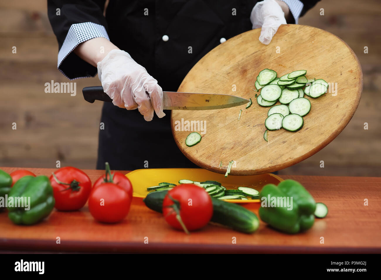The cook cuts fresh farm vegetables for dinner on the table Stock Photo ...