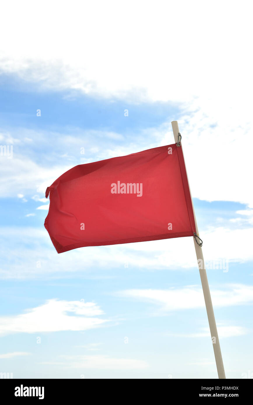 red flag on flag pole blowing in wind Stock Photo - Alamy