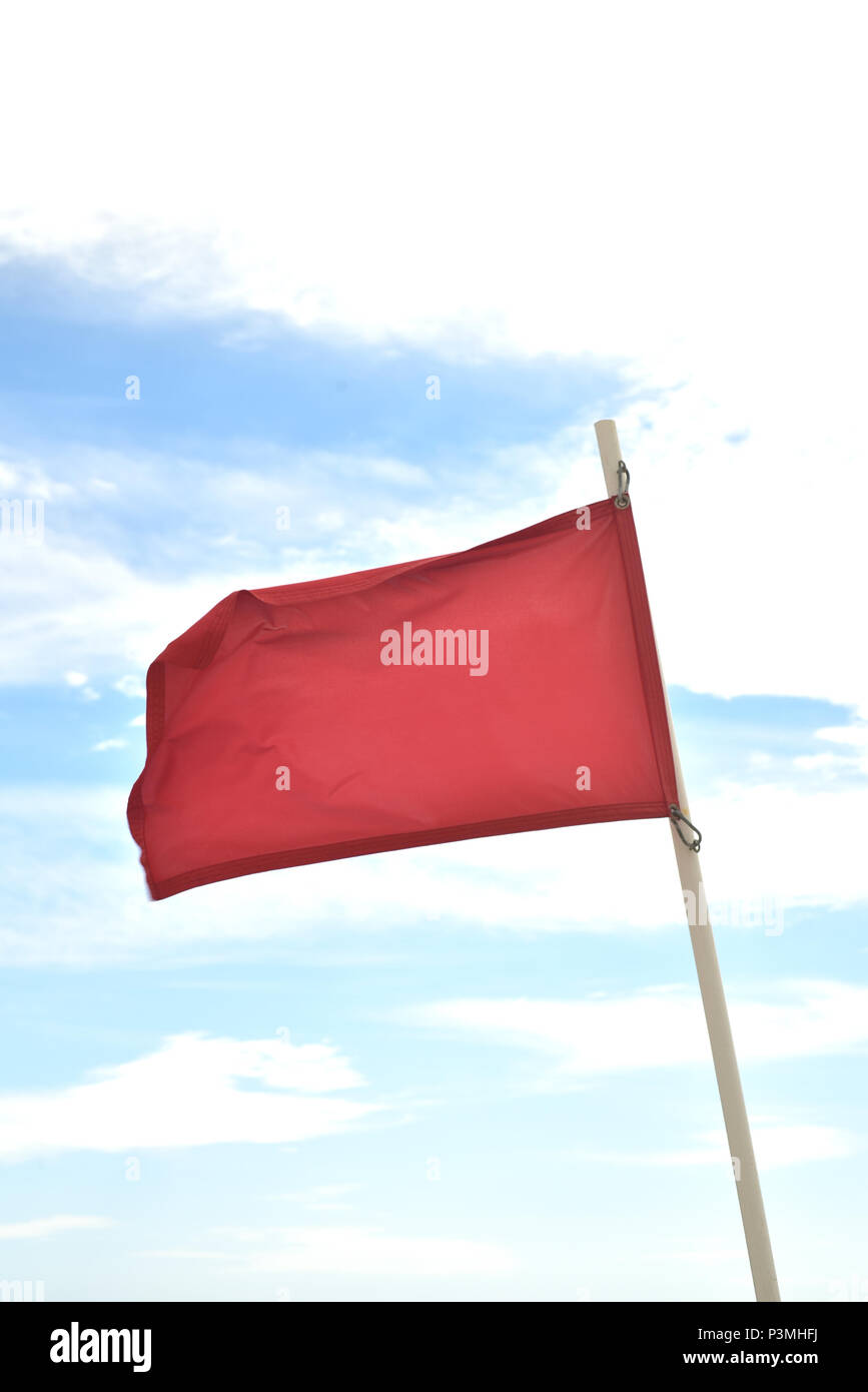 red flag on flag pole blowing in wind Stock Photo - Alamy