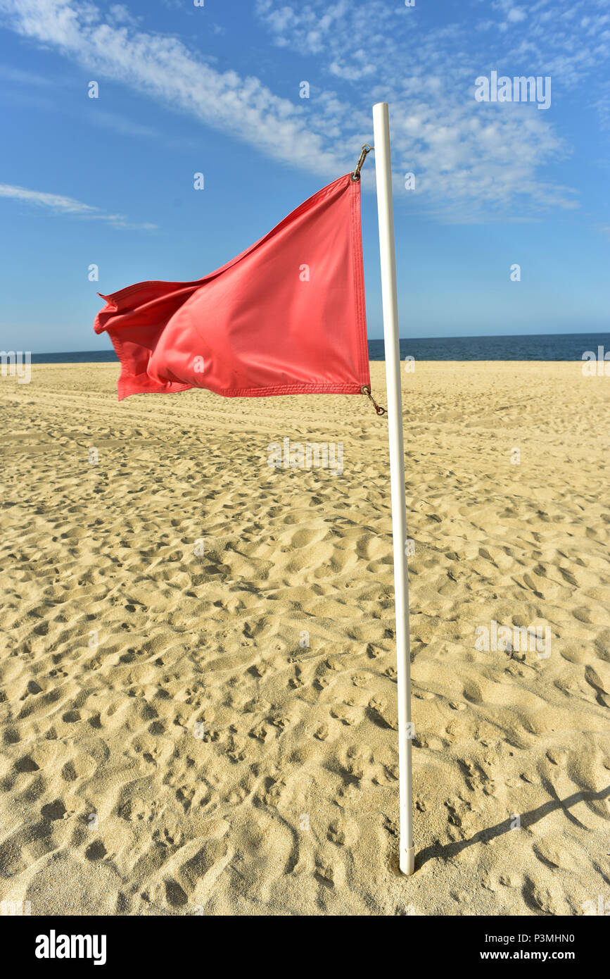 red flag on flag pole blowing in wind Stock Photo - Alamy