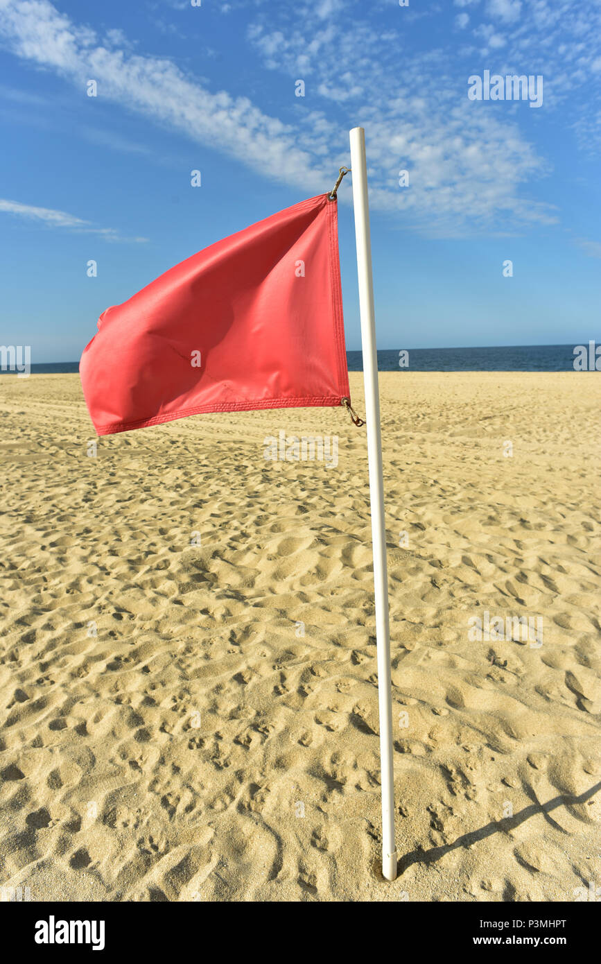 red flag on flag pole blowing in wind Stock Photo - Alamy