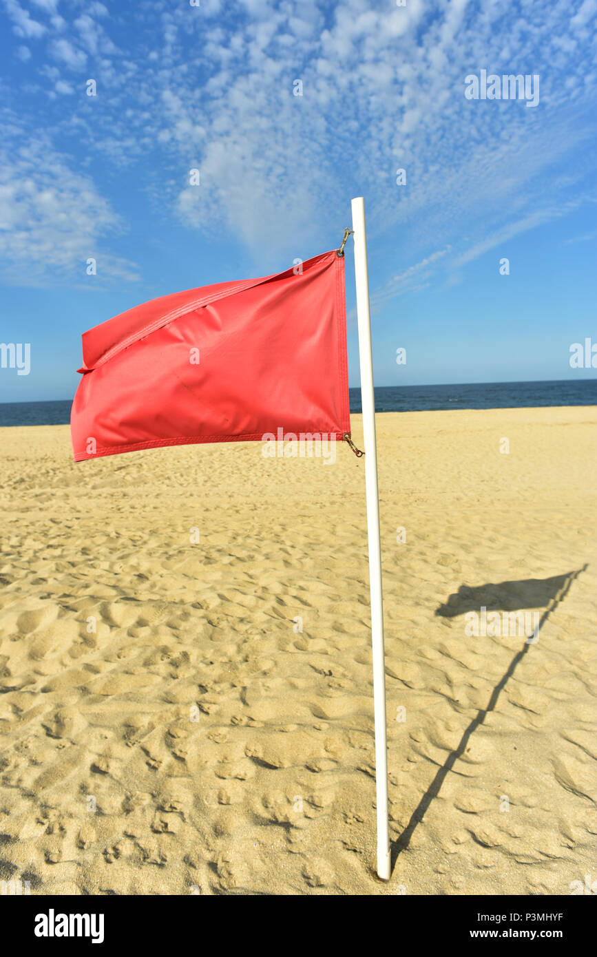 red flag on flag pole blowing in wind Stock Photo - Alamy