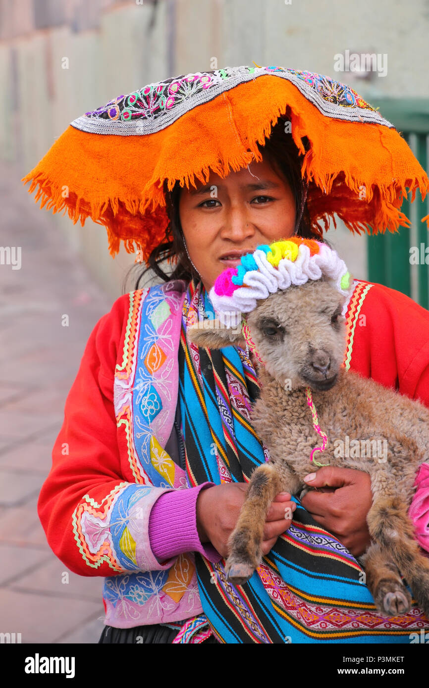 Local woman in traditional dress holding lamb in the street of Cusco ...