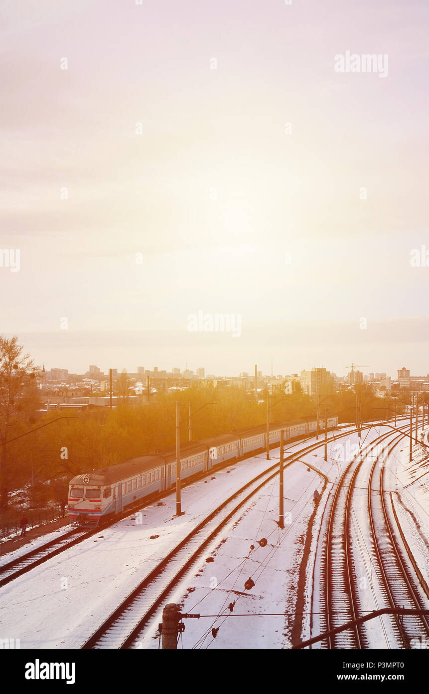 Winter landscape with a railway train on a railway surrounded by a city ...