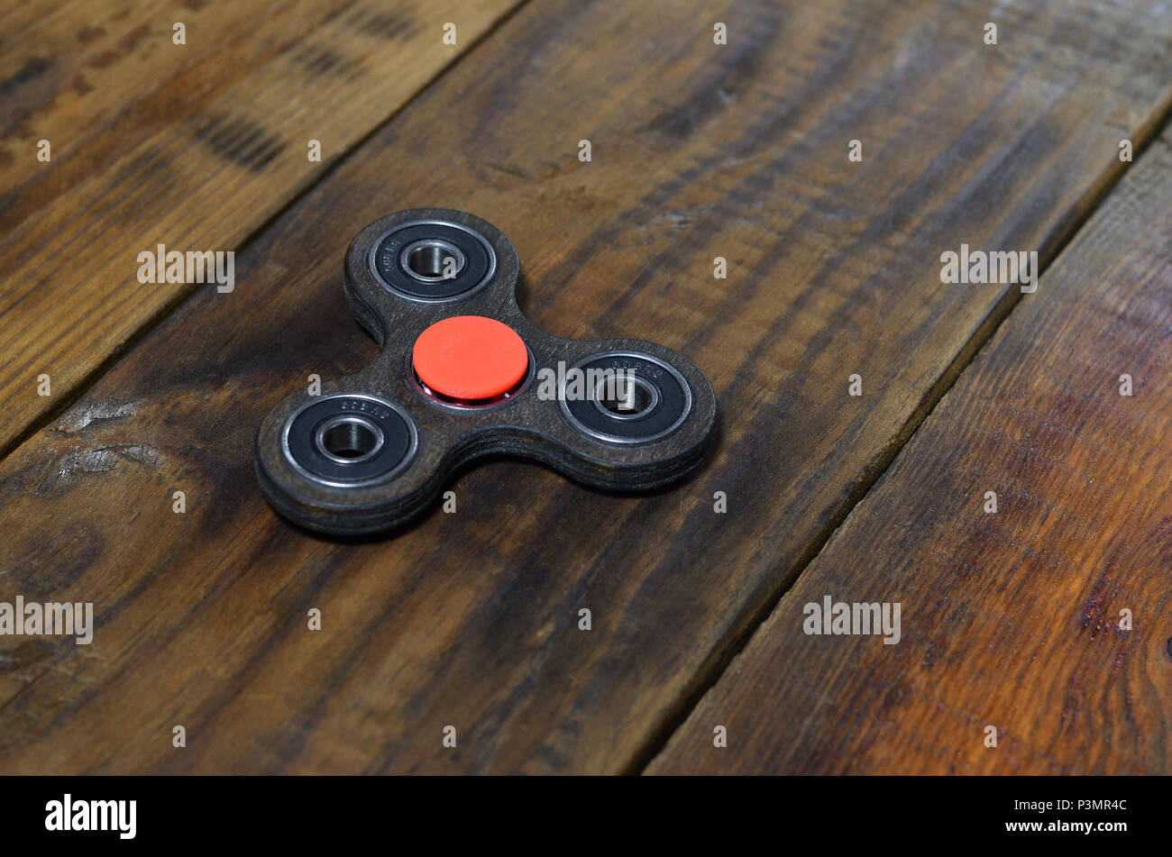 A rare handmade wooden fidget spinner lies on a brown wooden background ...