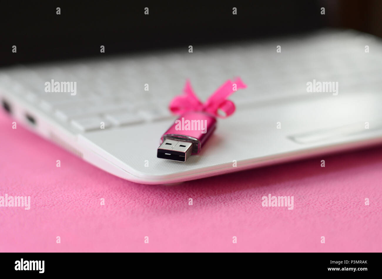 Brilliant pink usb flash memory card with a pink bow lies on a blanket ...