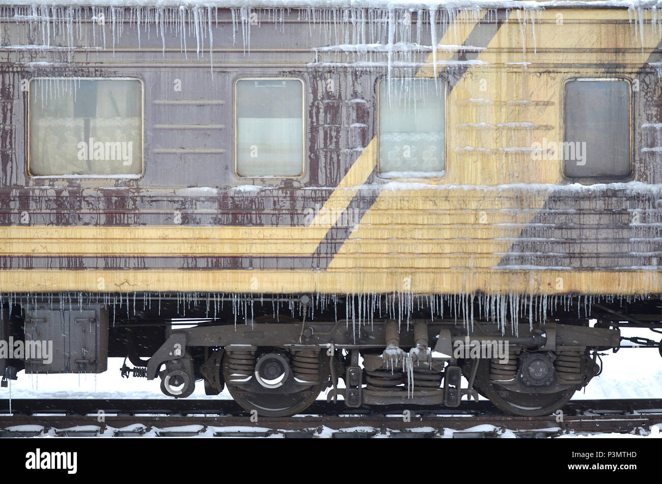 Detailed photo of a frozen car passenger train with icicles and ice on ...