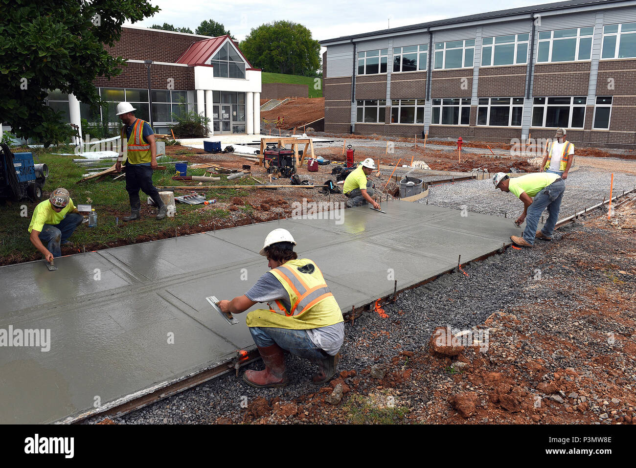 Concrete masons smooth a section of walkway leading to Spruance Hall ...