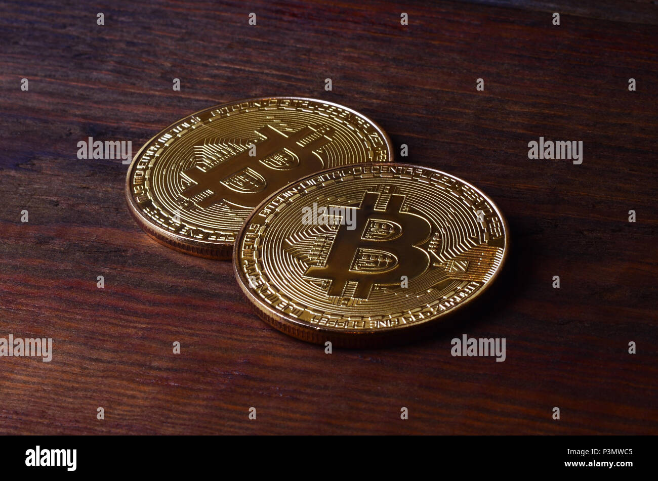 Two new golden physical bitcoins lies on dark wooden backgound, close ...