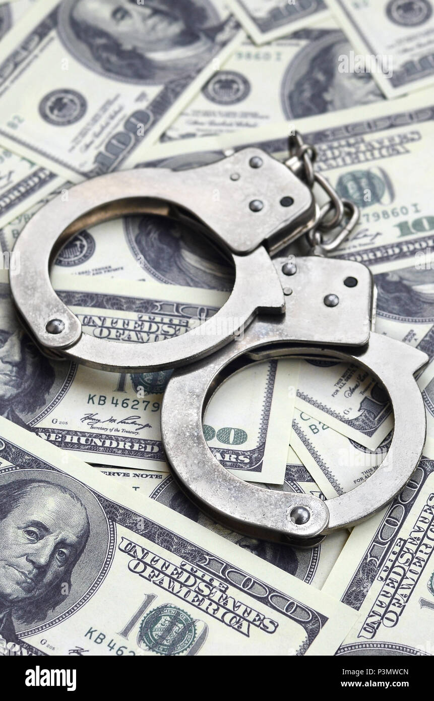 Police handcuffs lie on a lot of dollar bills. The concept of illegal ...