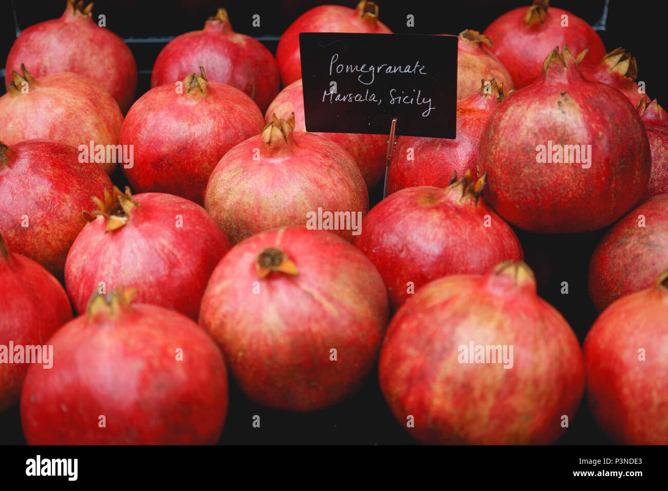 Close up view of a group of red pomegranates with a black tag on a ...
