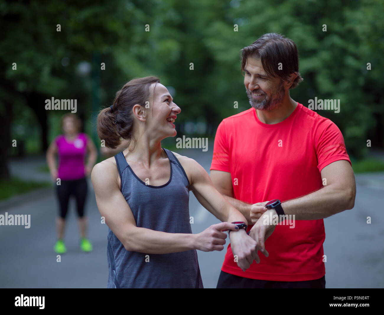 Young sporty couple using smart watches starting their timer before ...