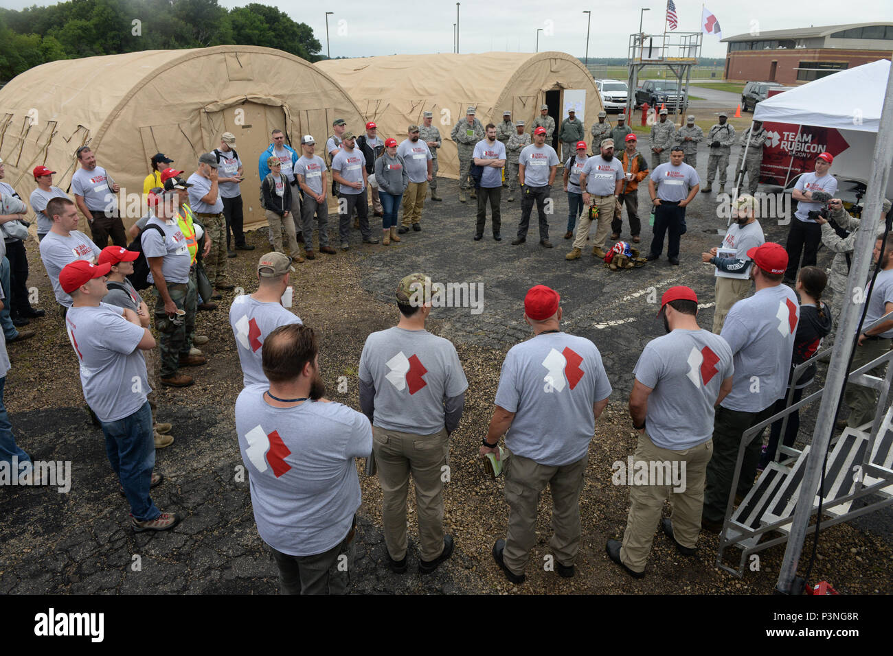 Members of Team Rubicon, grey shirts, form a circle as they meet to ...