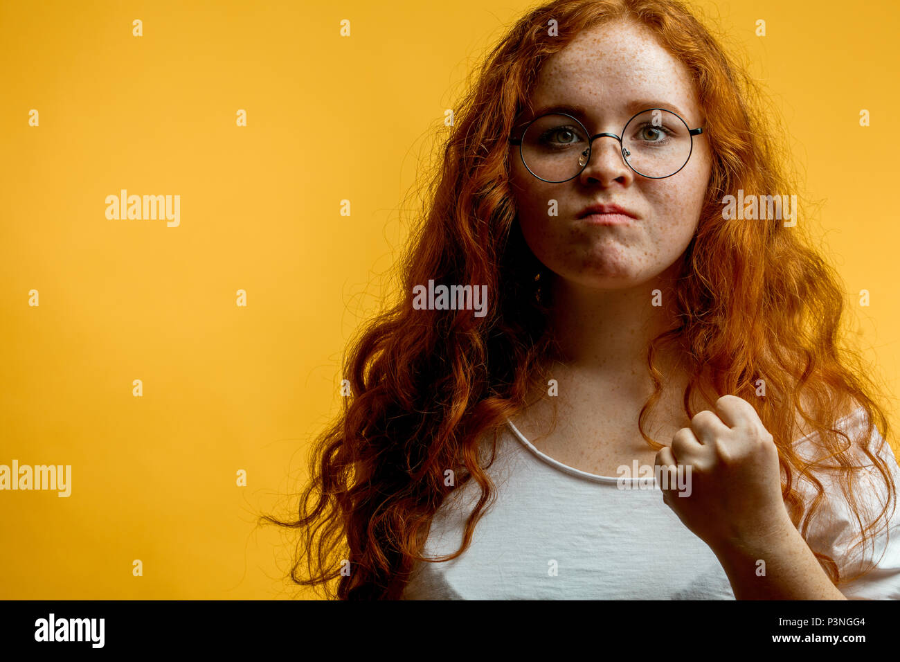 Young pretty ginger woman shows fist, with angry or aggressive ...