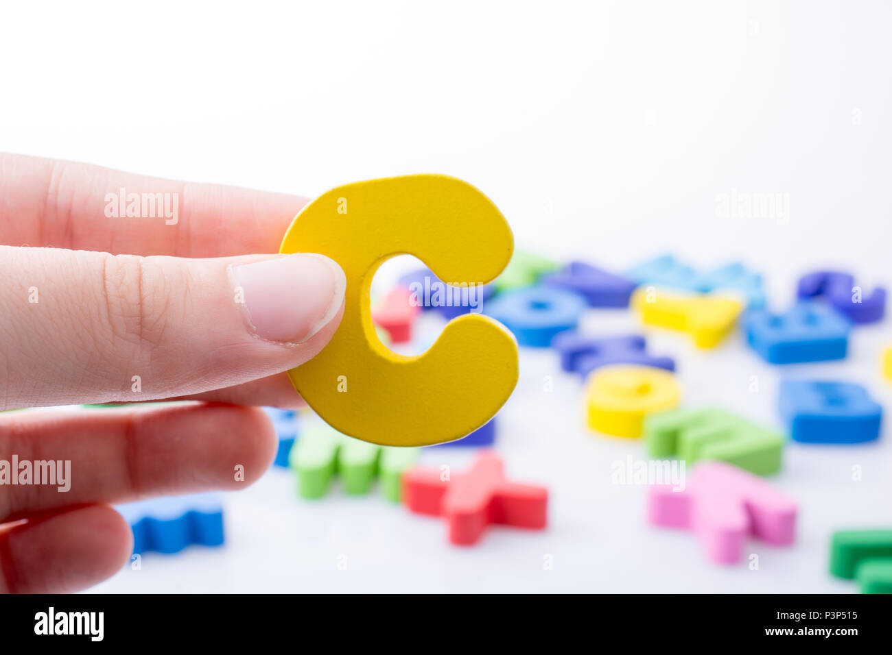 Letter C in hand beside colorful alphabet letter blocks scattered ...