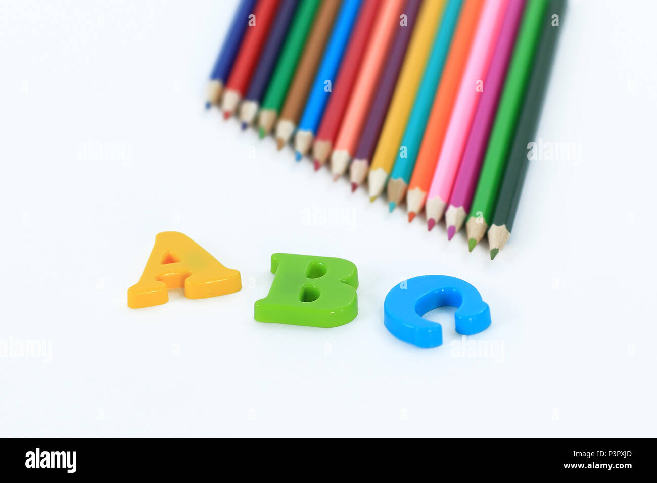colored pencils and letters of the alphabet on a white background ...