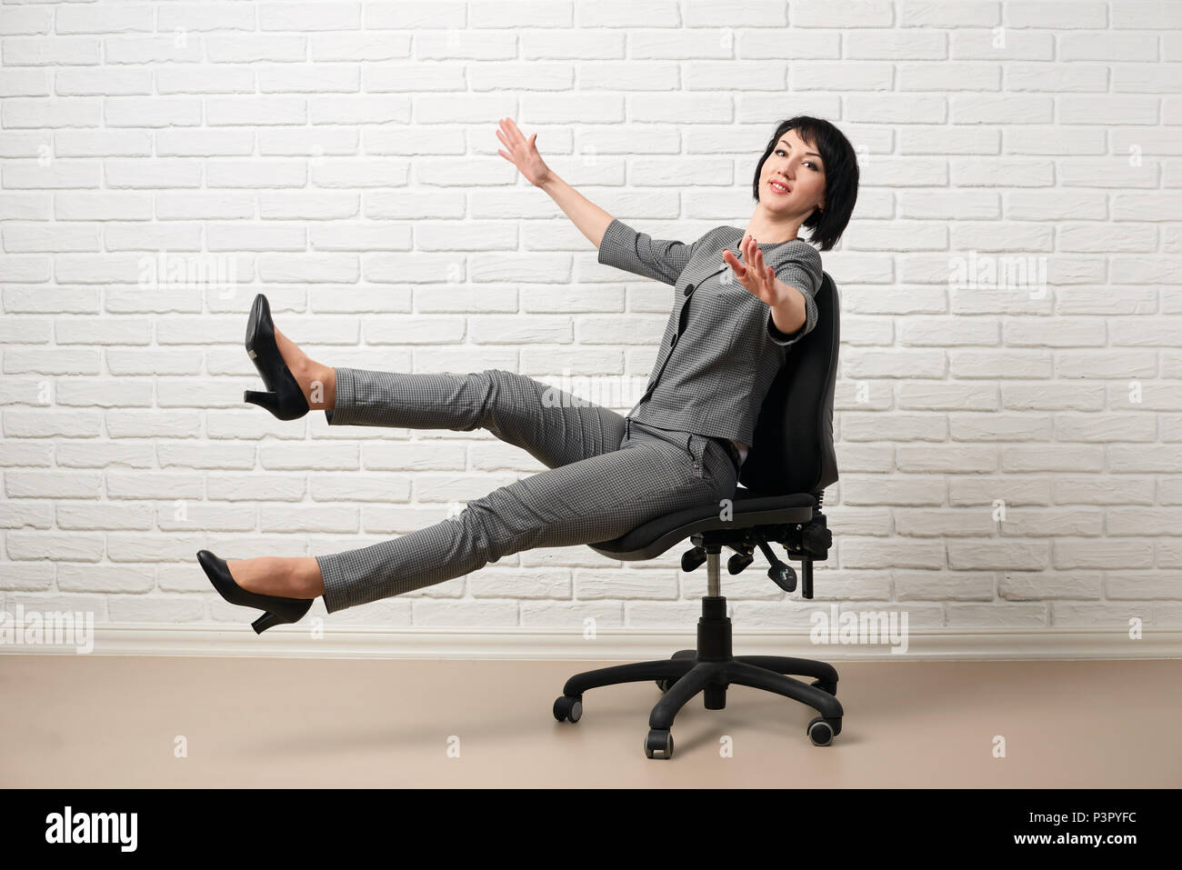 the business woman having fun, falls from chair, dressed in a gray suit ...
