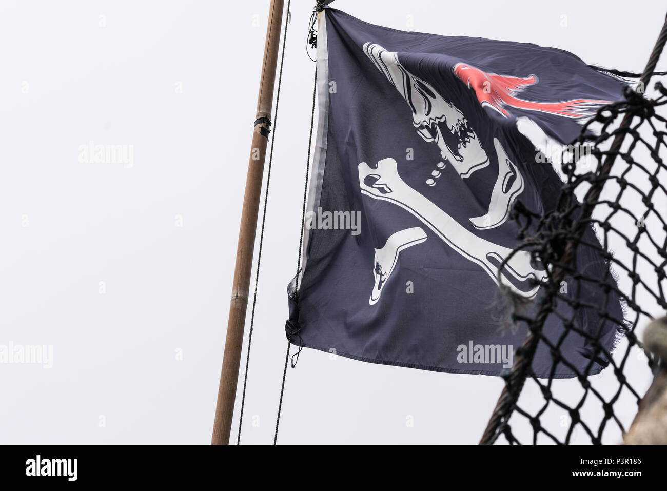 Pirate flag fluttering in the wind on a mast of a pirate ship replica ...
