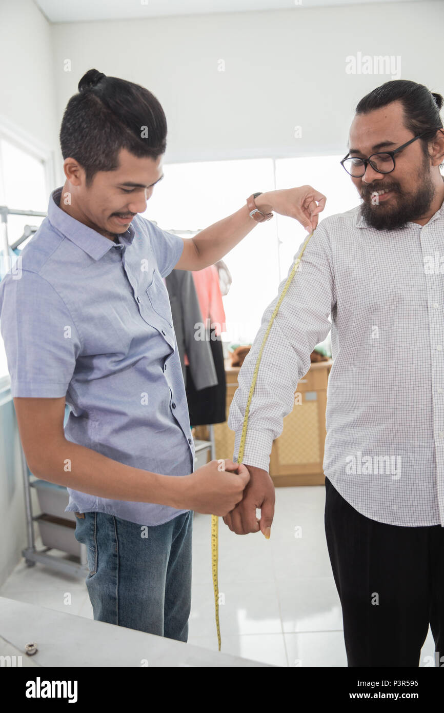 fashion designer taking measure of customer body Stock Photo - Alamy