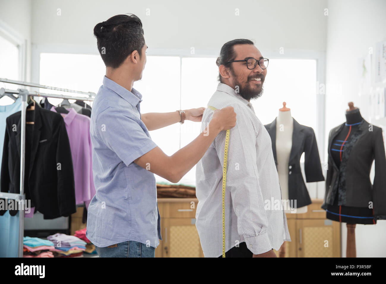 fashion designer taking measure of customer body Stock Photo - Alamy