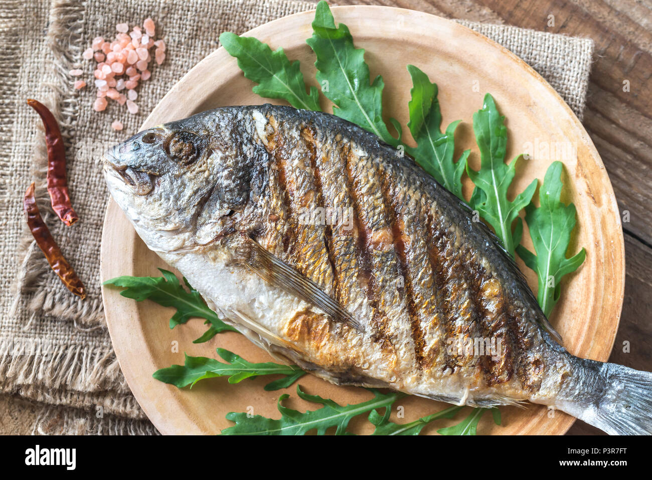 Grilled gilt-head bream with fresh arugula on the plate Stock Photo - Alamy