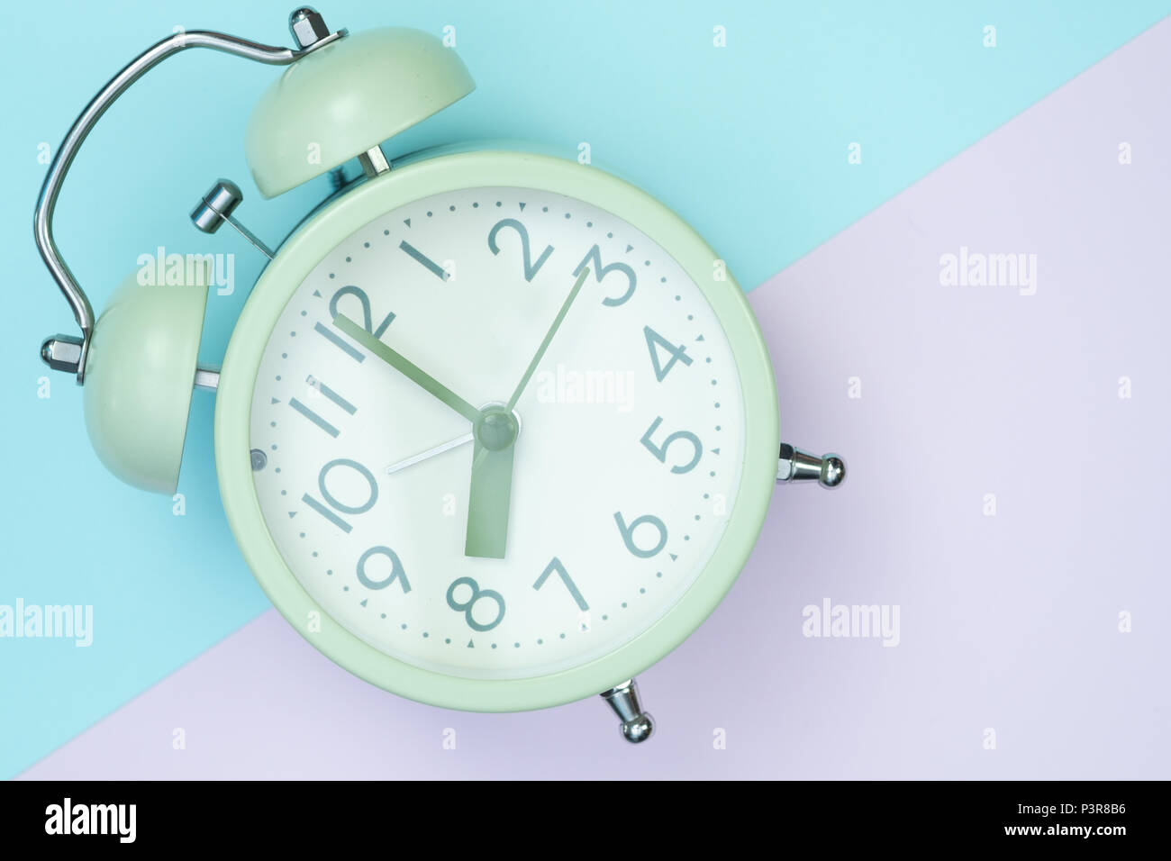Flat lay vintage alarm clock on sweet pastel colored paper top view ...