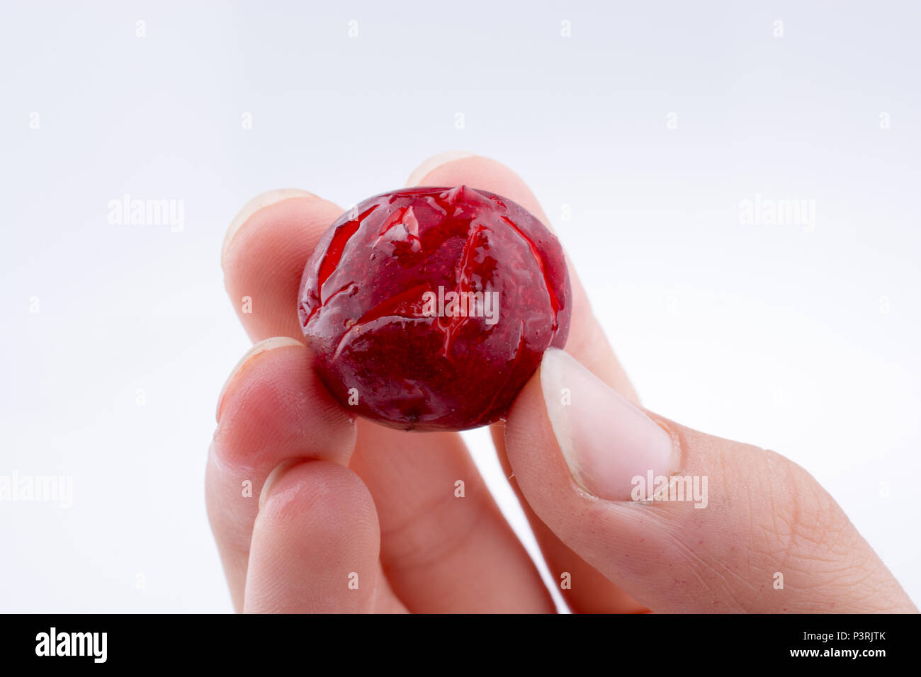 Hand holding a Cherry on a white background Stock Photo - Alamy