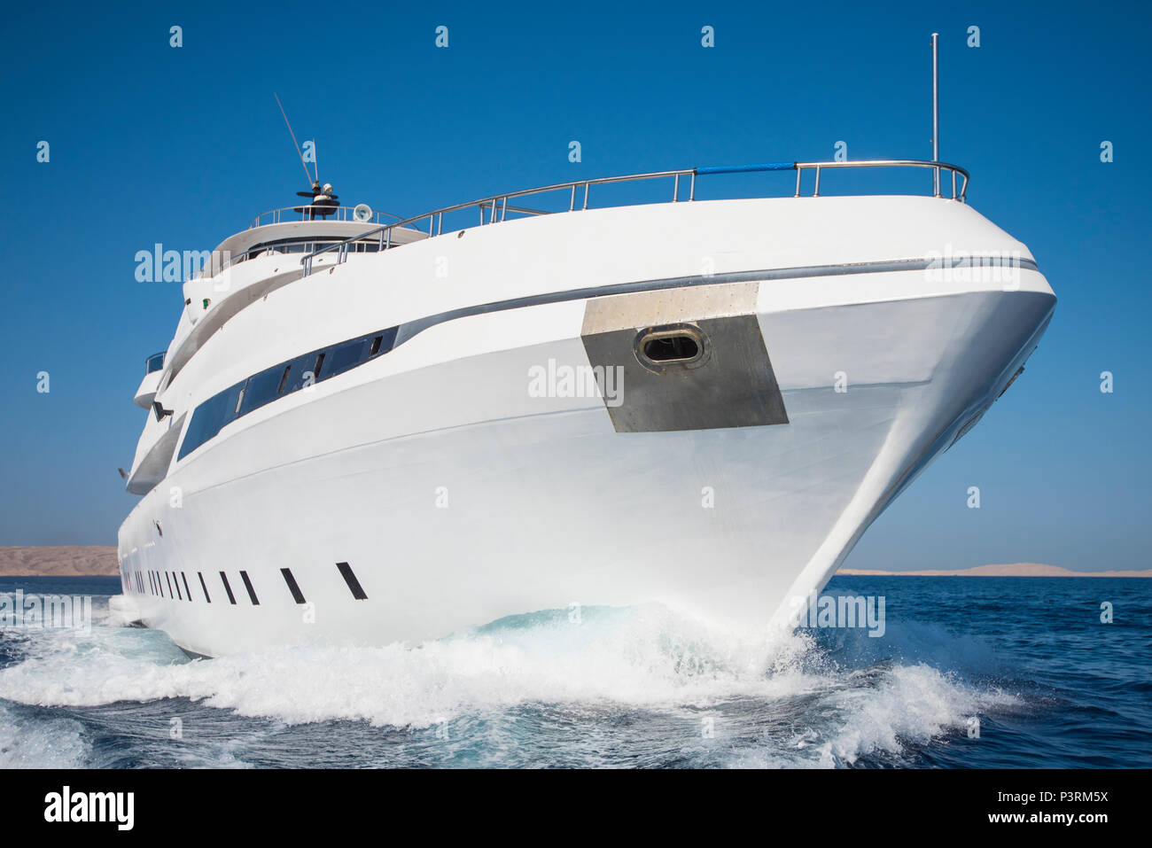 A luxury private motor yacht under way on tropical sea with bow wave ...