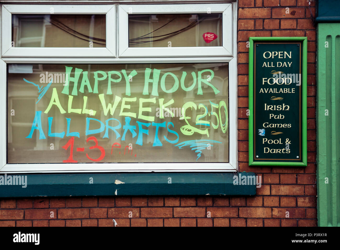 An old run down pub front with signs and fence in an inner city street ...