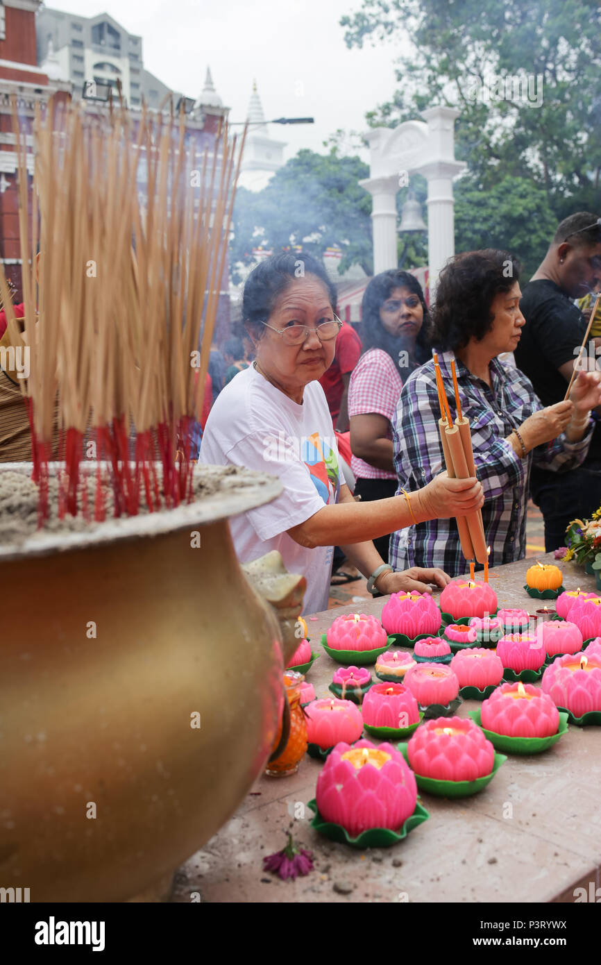 Buddhists praying with joss sticks and lotus candles at Maha Vihara ...