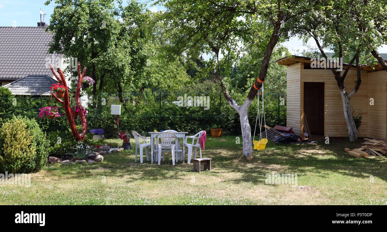 Backyard of an ordinary poor village house-- plastic furniture, a swing ...