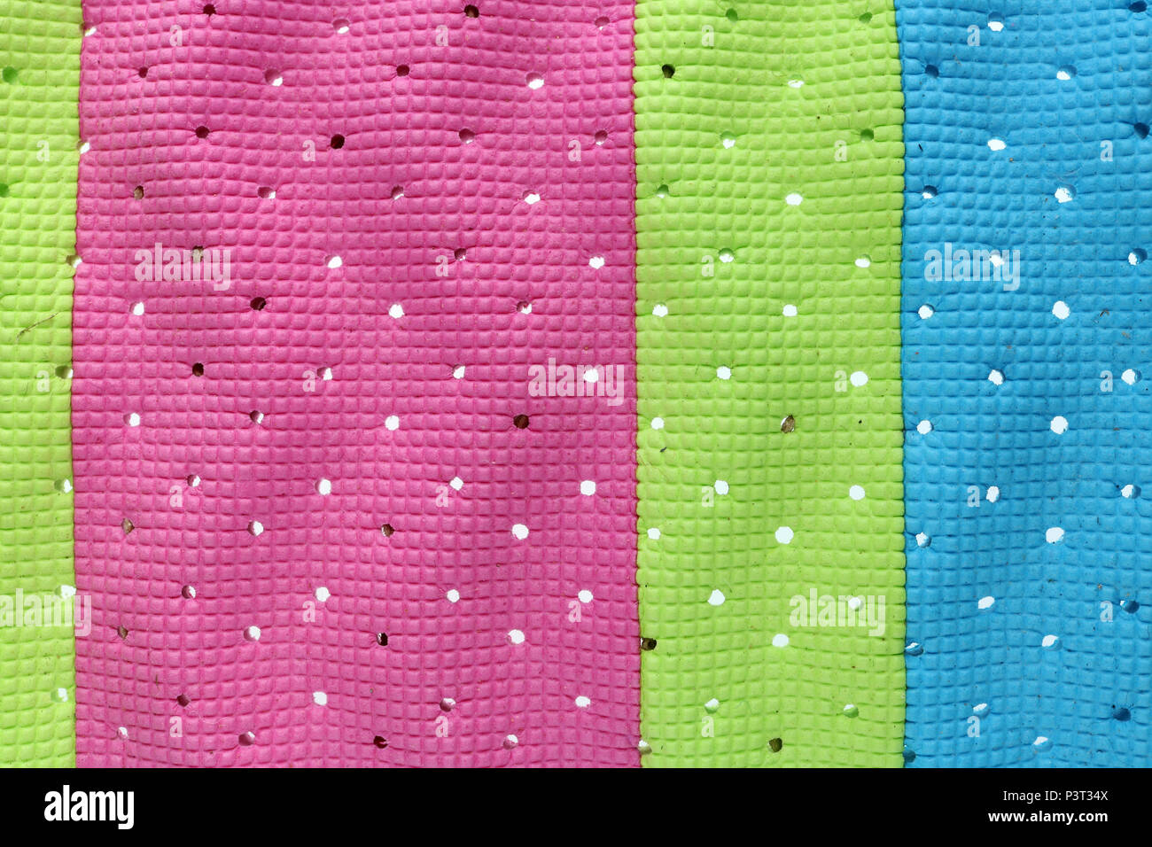 Wavy surface of strips of multi-colored soft plastic insol with holes ...