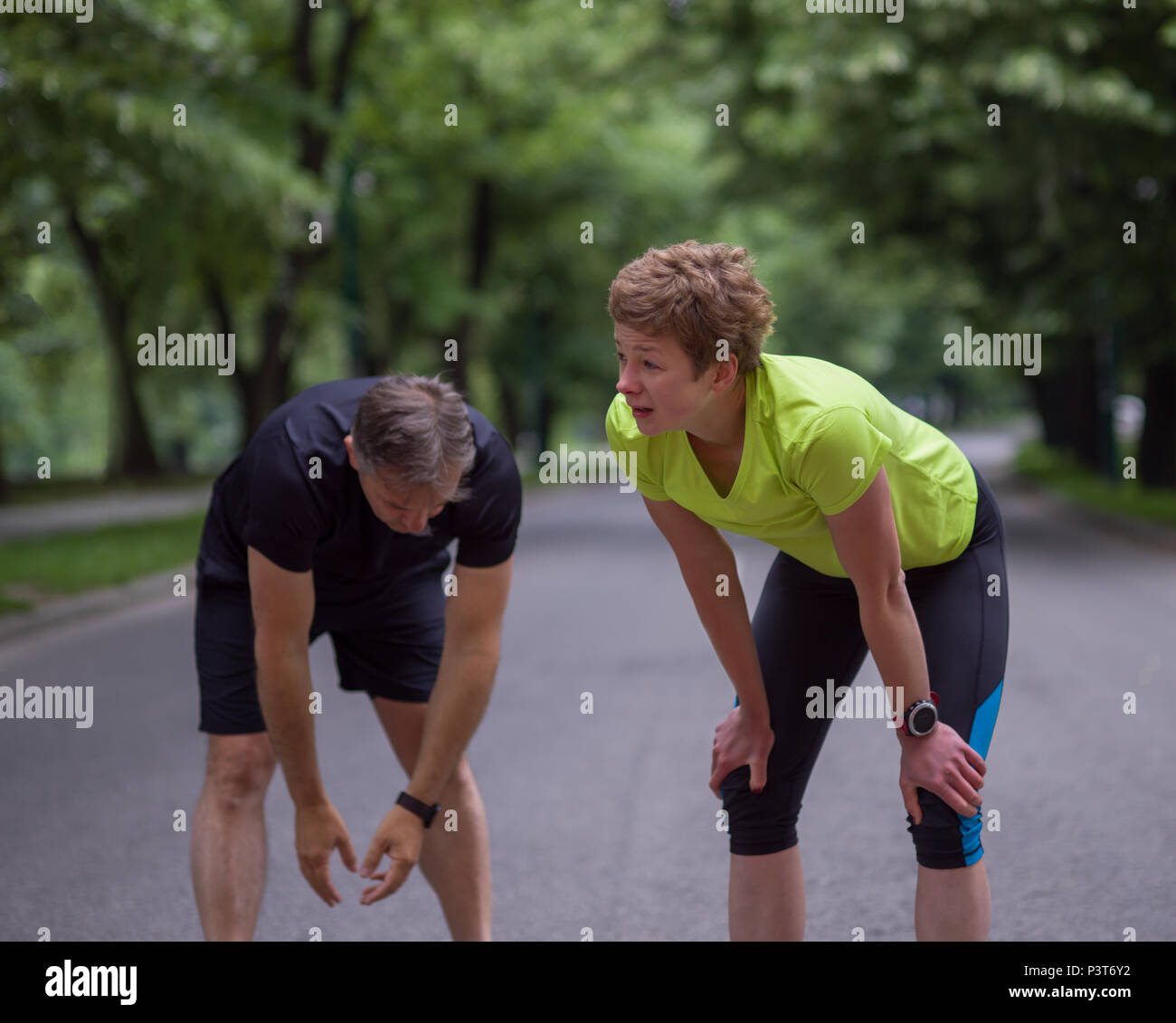healthy runners team warming up and stretching in city park before ...