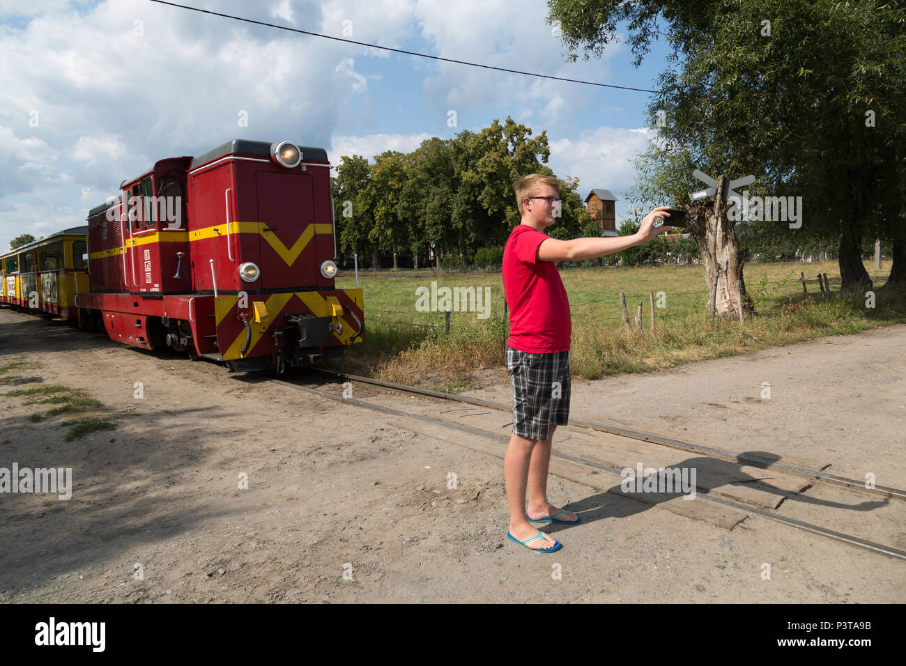 Poland, Mikoszewo, teenager tourist takes a selfie with narrow gauge ...