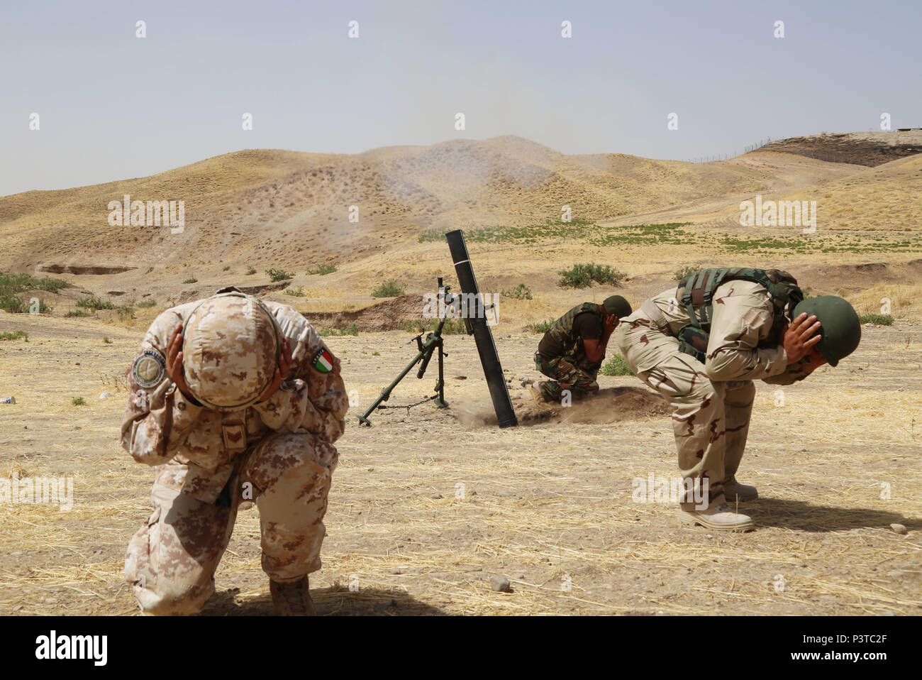 An Italian trainer and Peshmerga soldiers turn as an M120 120mm mortar ...
